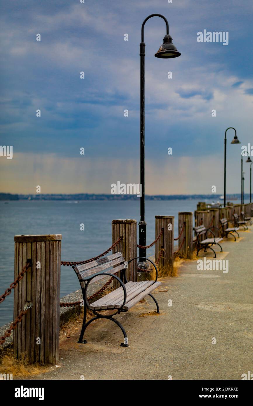Promenade with benches and lamp posts along a waterfront with rain ...