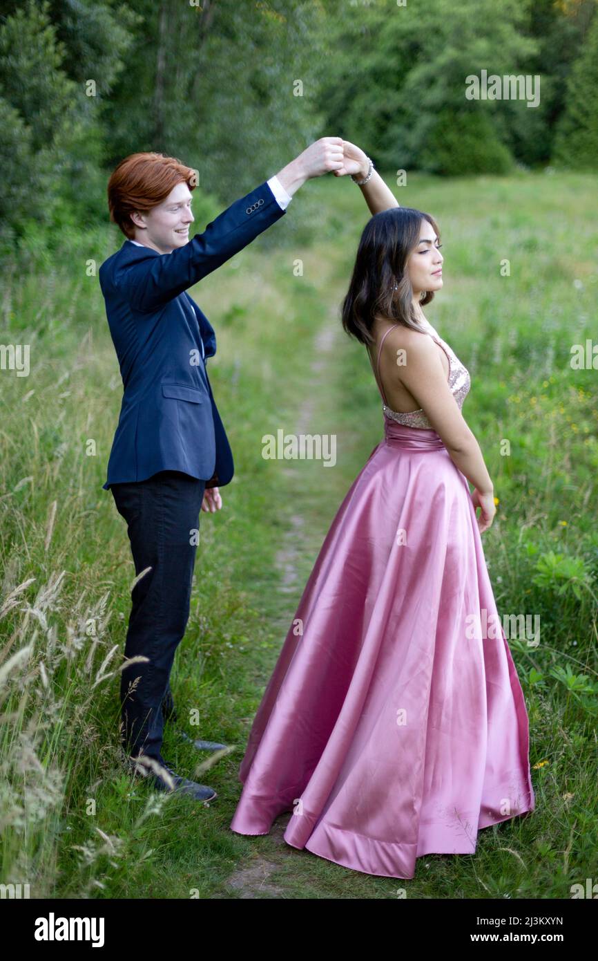 Young couple dancing in formal wear on a worn path in a park area ...