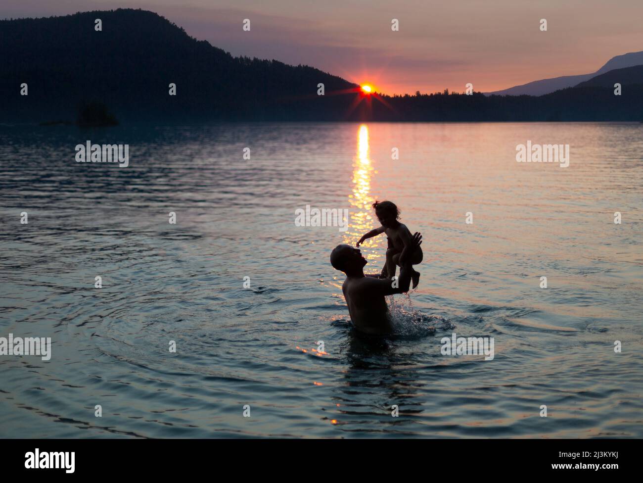 Father and young daughter play in a lake at sunset, Ruby Lake on the ...