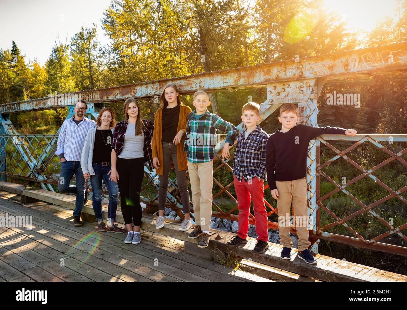 Family of seven standing on a bridge for a family portrait in a city ...