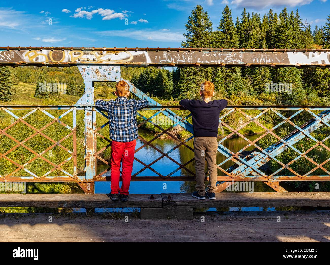 Two boys look out from a park bridge to a creek below; Edmonton ...