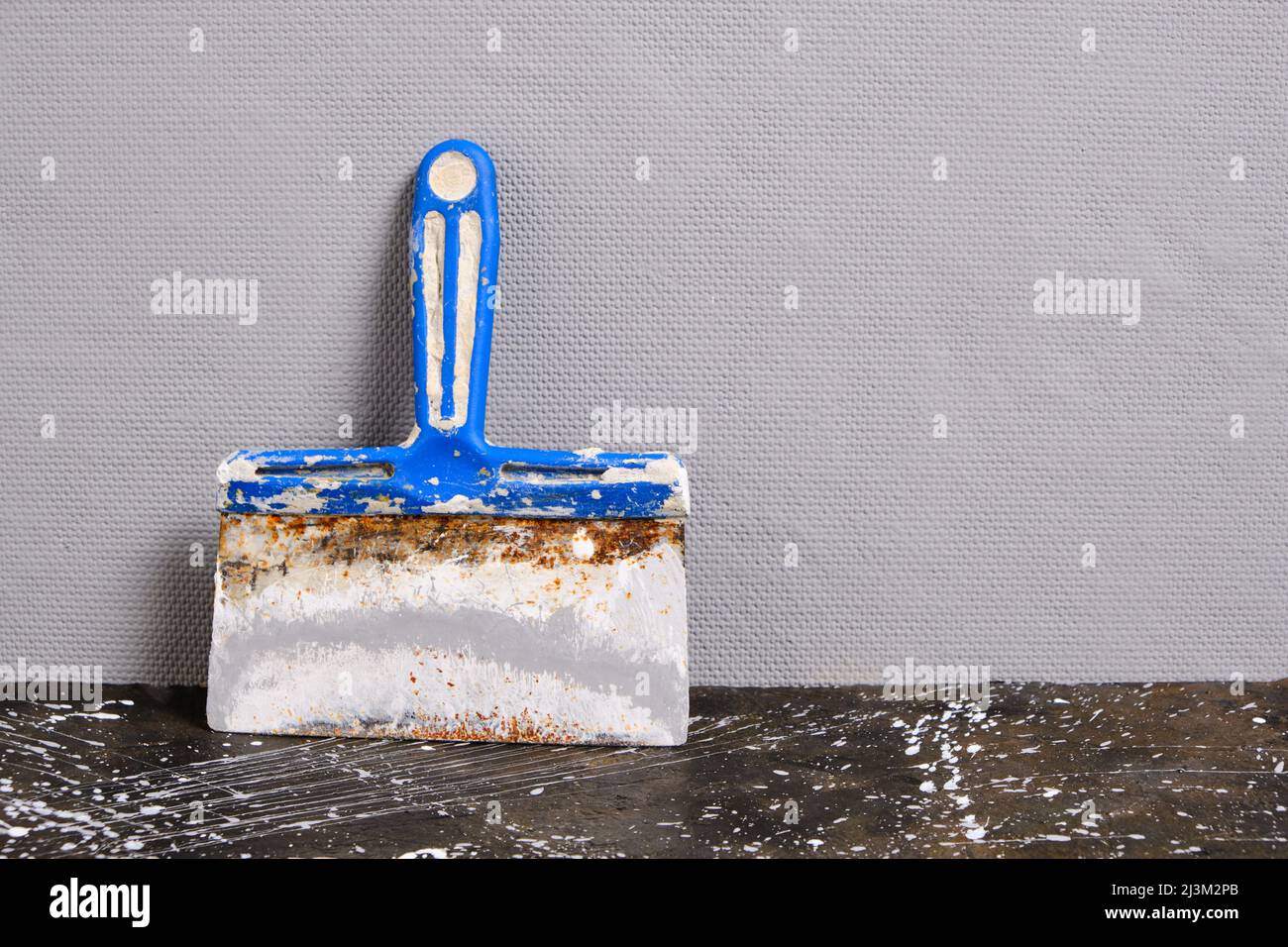 Spatula for finishing and plastering walls on a gray wall background ...