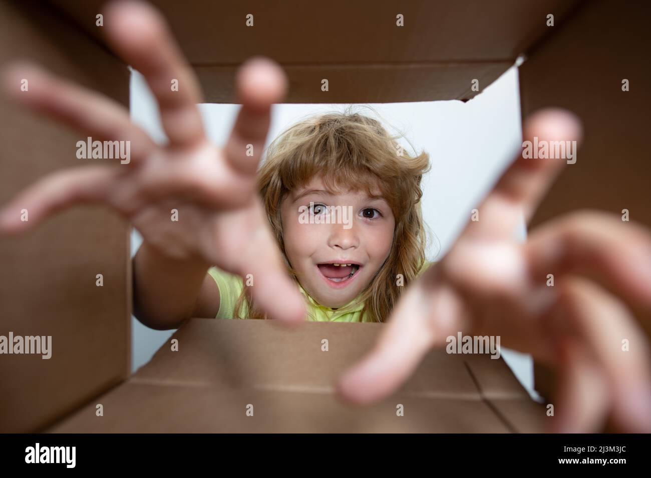 Child age 10 year opens carton box and pulling out gift from it. Small ...