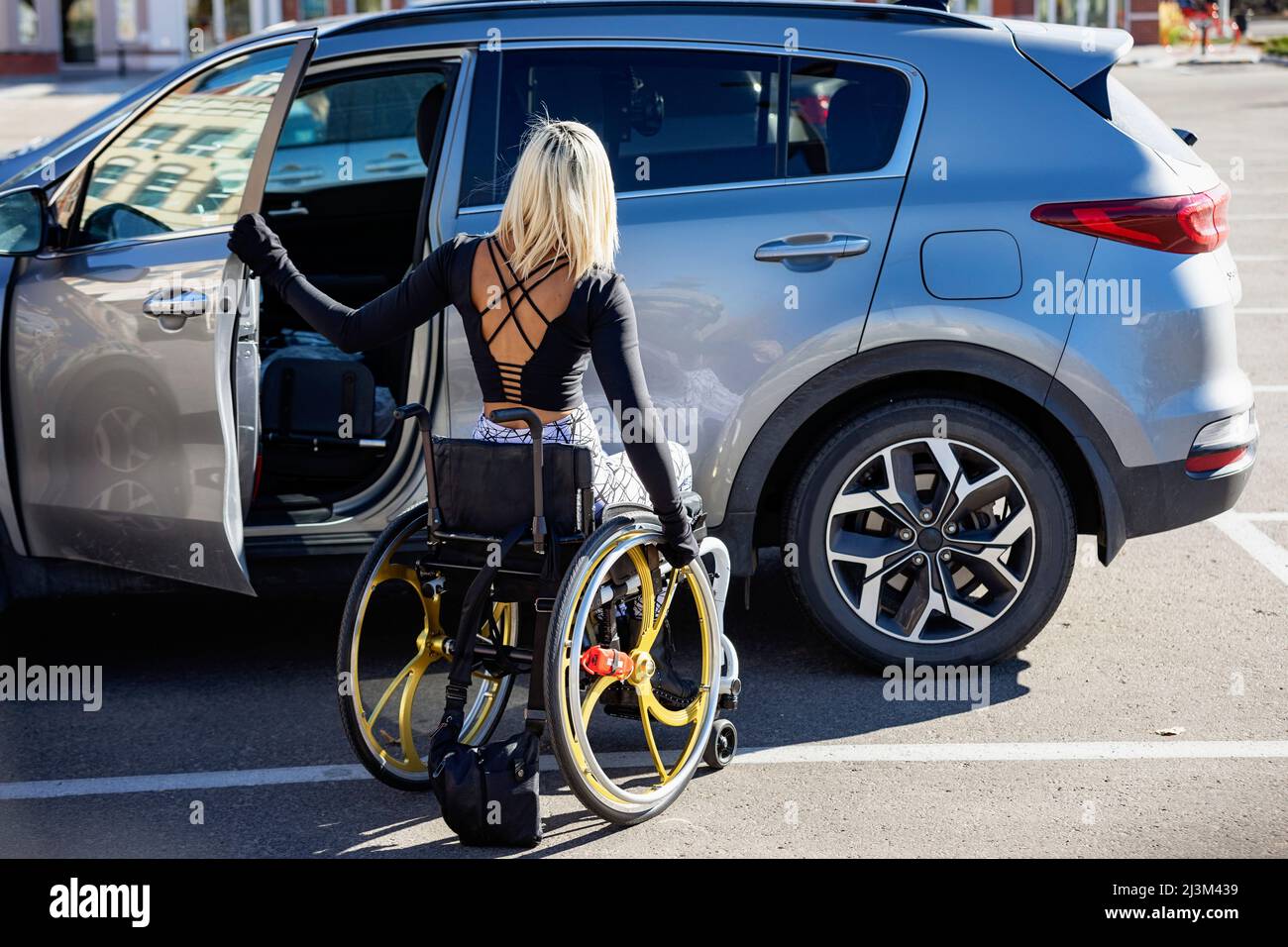 Young paraplegic woman moves from her vehicle to her wheelchair in a ...