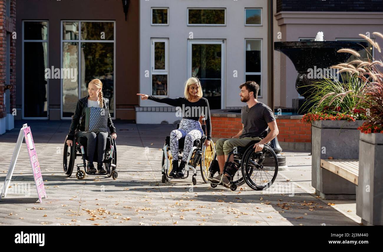 Three young paraplegic friends spending time together shopping outside ...