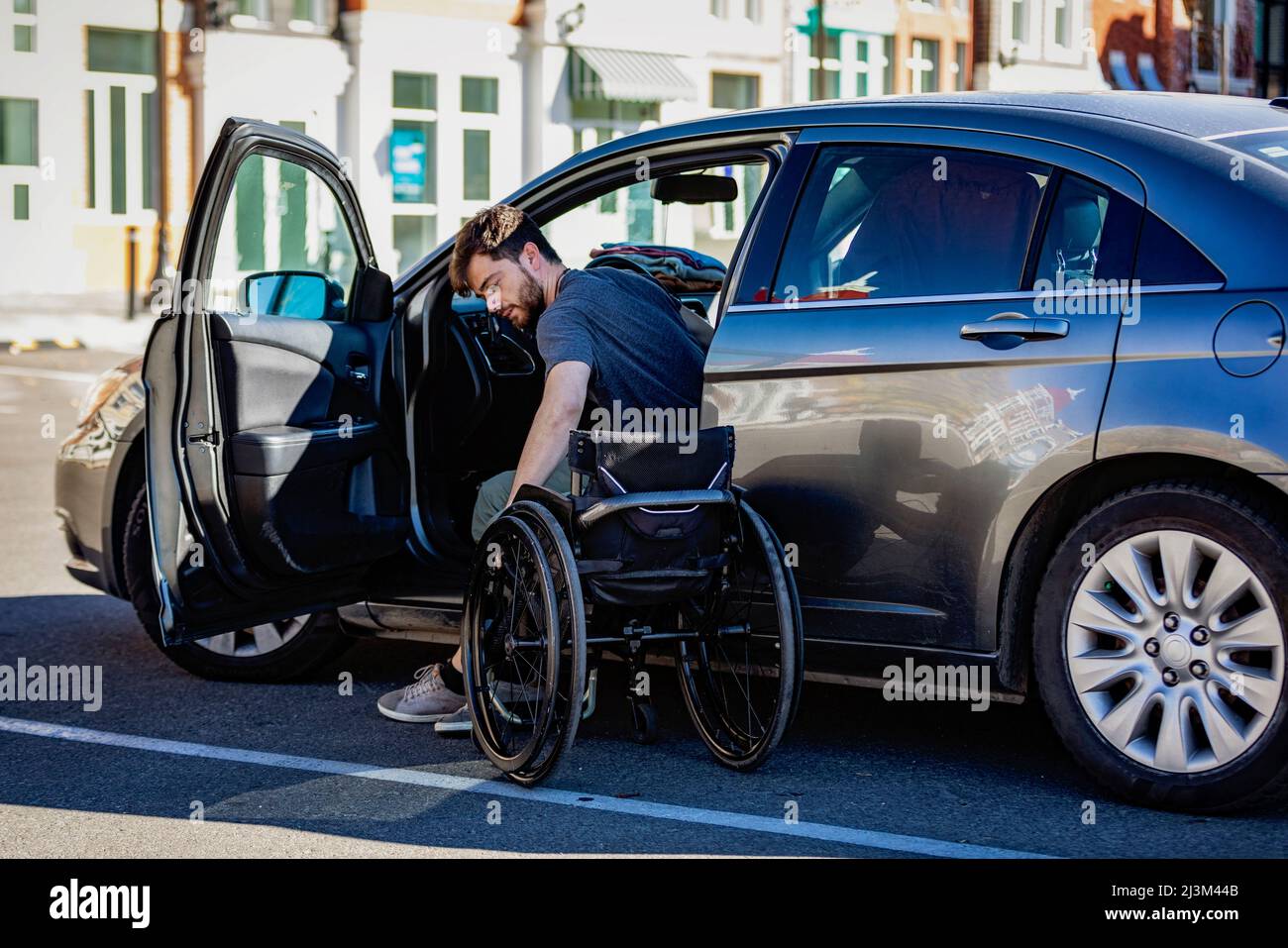 Young paraplegic man moves from his wheelchair to the driver's seat of ...