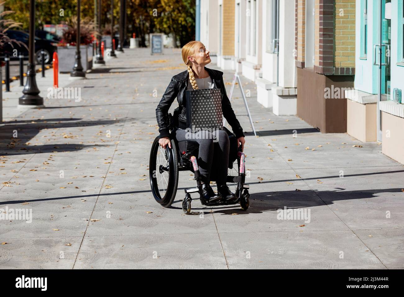 Young paraplegic woman in her wheelchair with a shopping bag going down ...