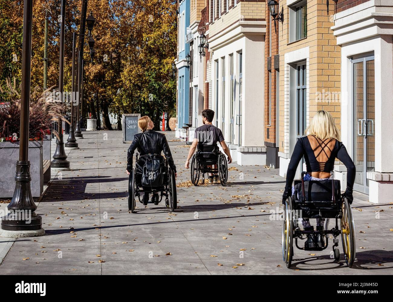 Three young paraplegic friends spending time together moving down a ...