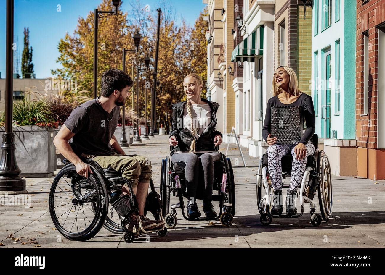 Young paraplegics in their wheelchairs visiting together on a walkway ...