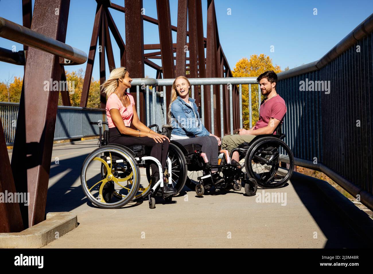 Group of three young paraplegics in their wheelchairs visiting together ...