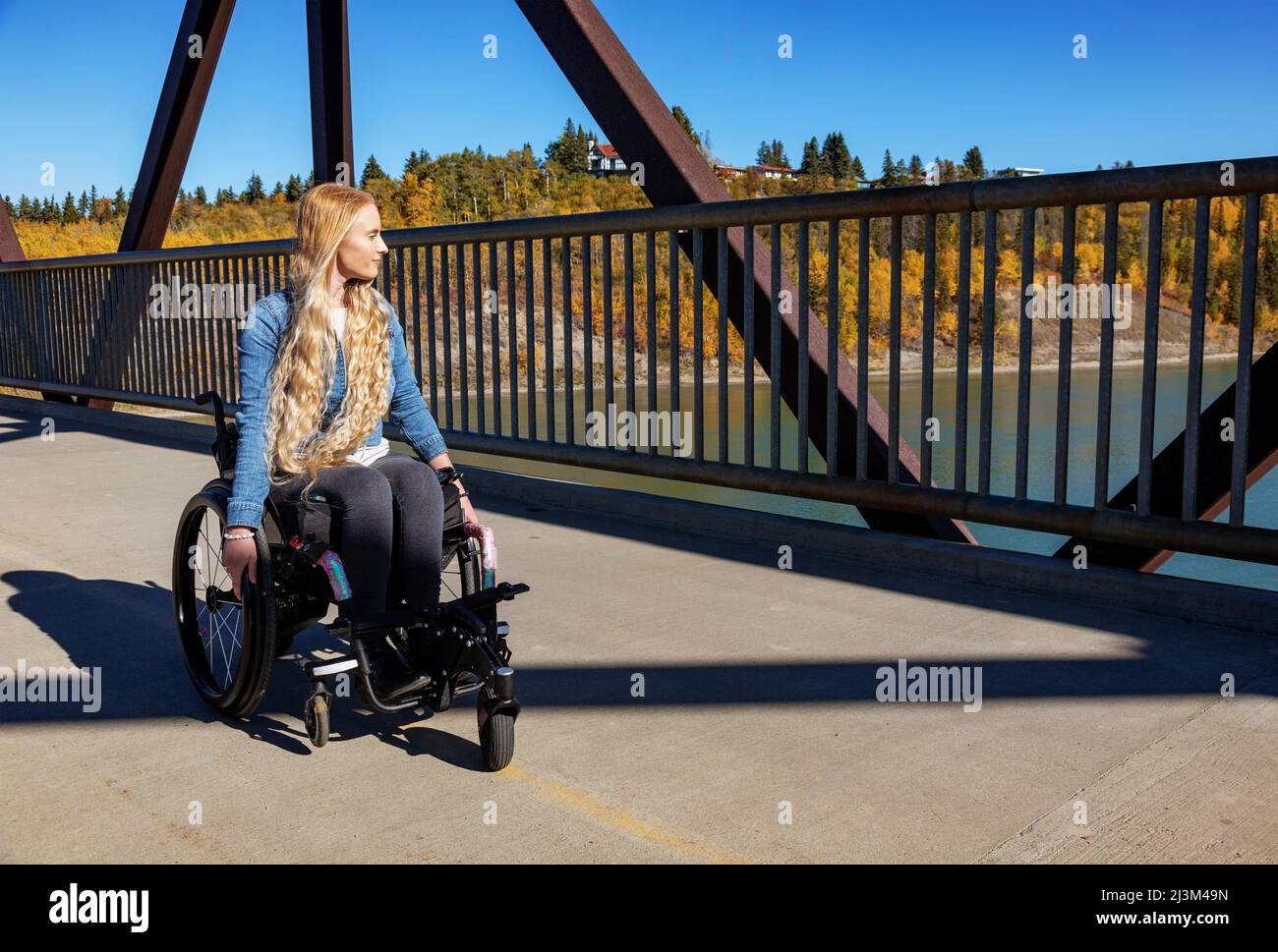 Young paraplegic woman going across a bridge using her wheelchair on a ...