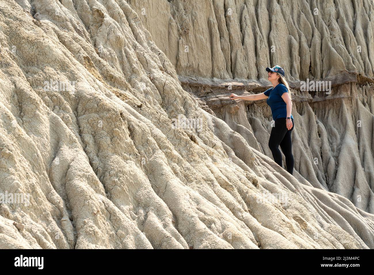 Woman standing on the eroded slopes in Big Muddy Badlands, viewing the ...