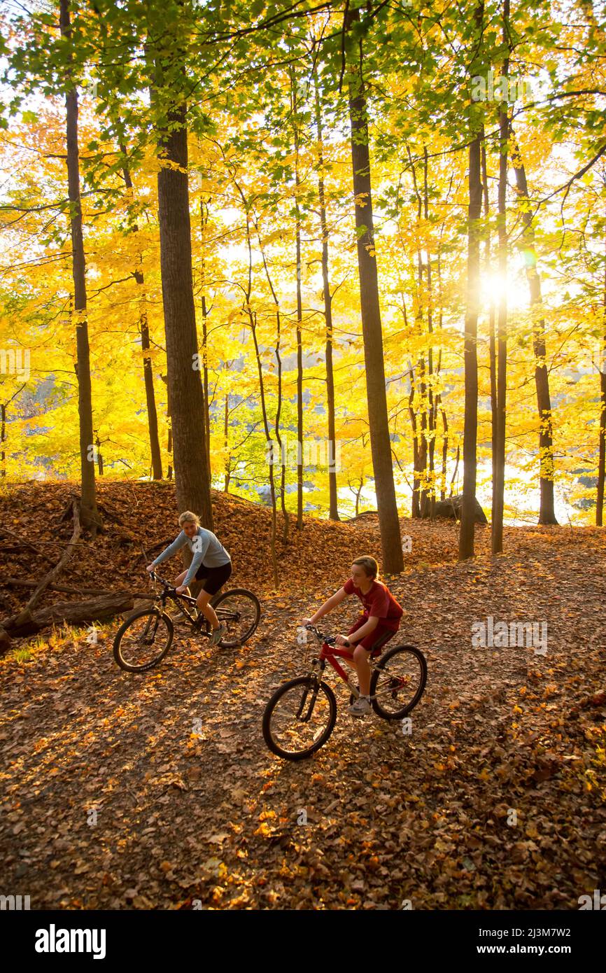 A boy and his mother ride bikes through brilliant Fall foliage near the ...