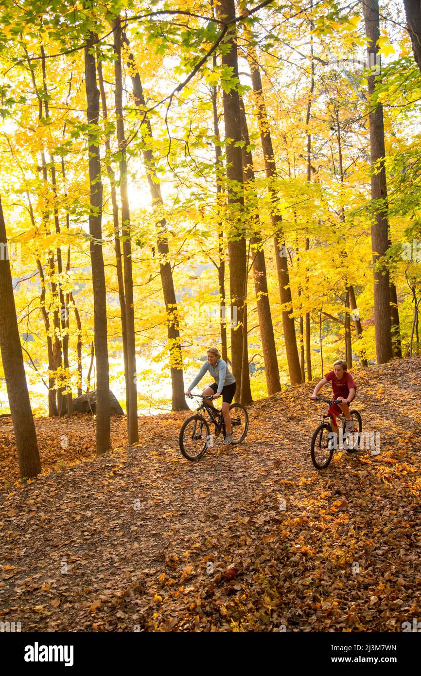 A boy and his mother ride bikes through brilliant Fall foliage near the ...
