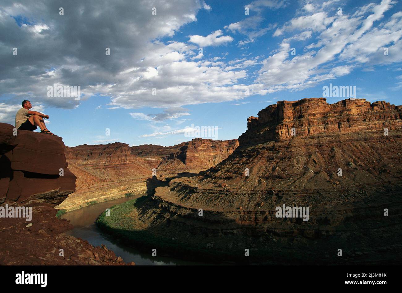Hiker sits on cliff's edge overlooking the Colorado River.; Cataract ...