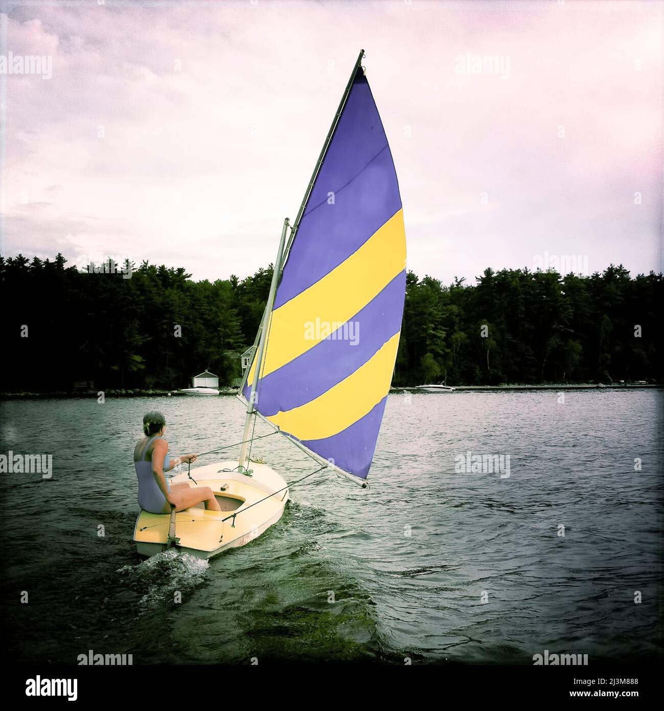 A woman sails a small boat across Sebago Lake.; Sebago Lake, Maine ...