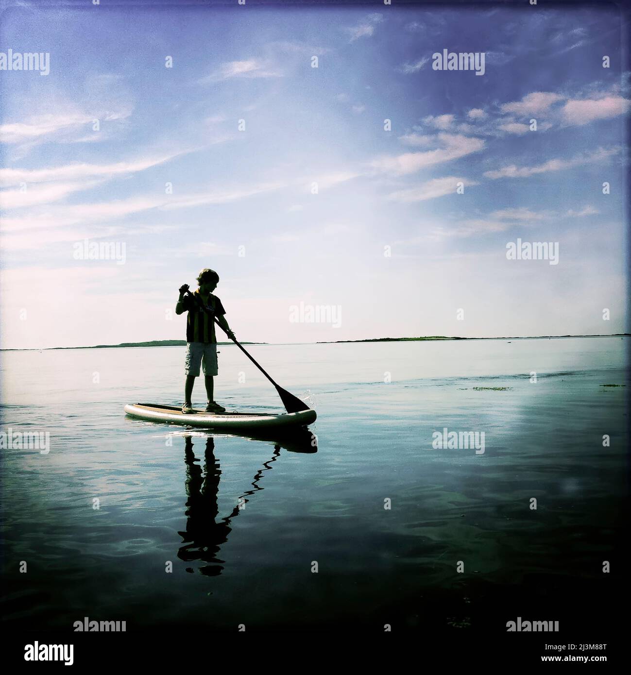 A ten year old boy on a stand up paddle board off Orr's Island.; Orr's ...