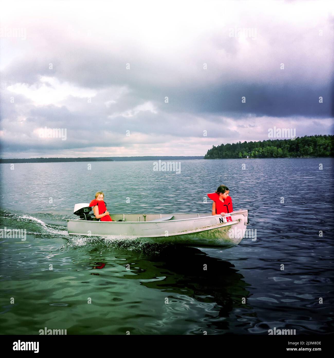 Seven and eight year old cousins drive their little aluminum motor boat across Sebago Lake ...