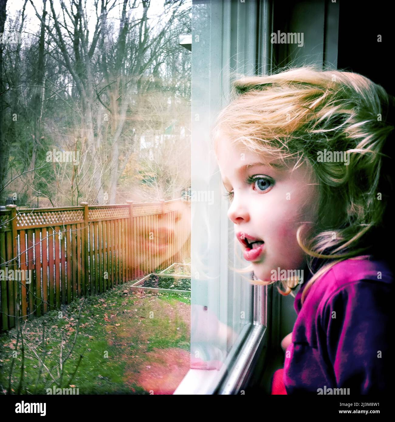 A pretty two year old girl looks out the window.; United States Stock ...