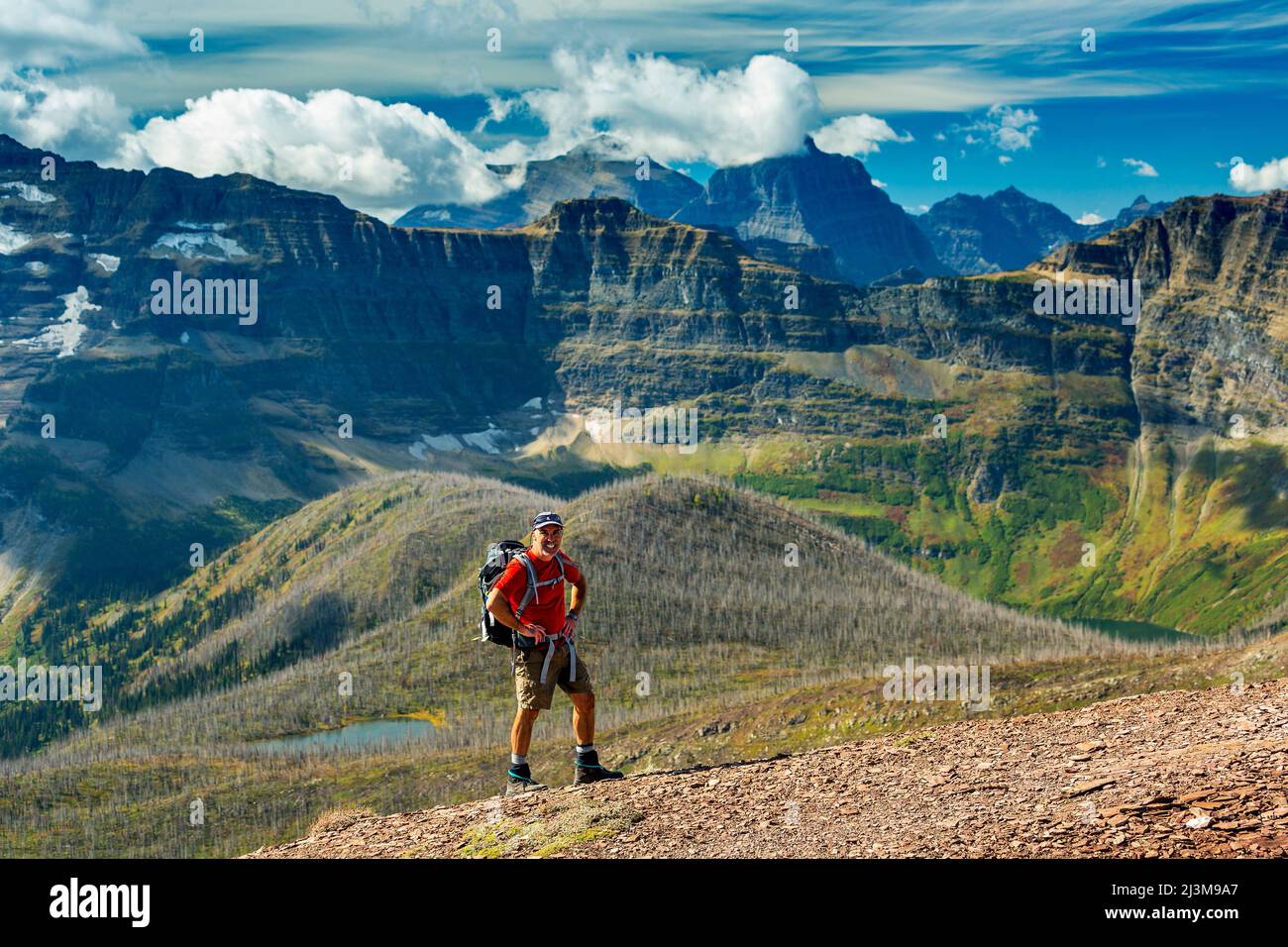 Male hiker on top of a mountain ridge overlooking a valley below and ...