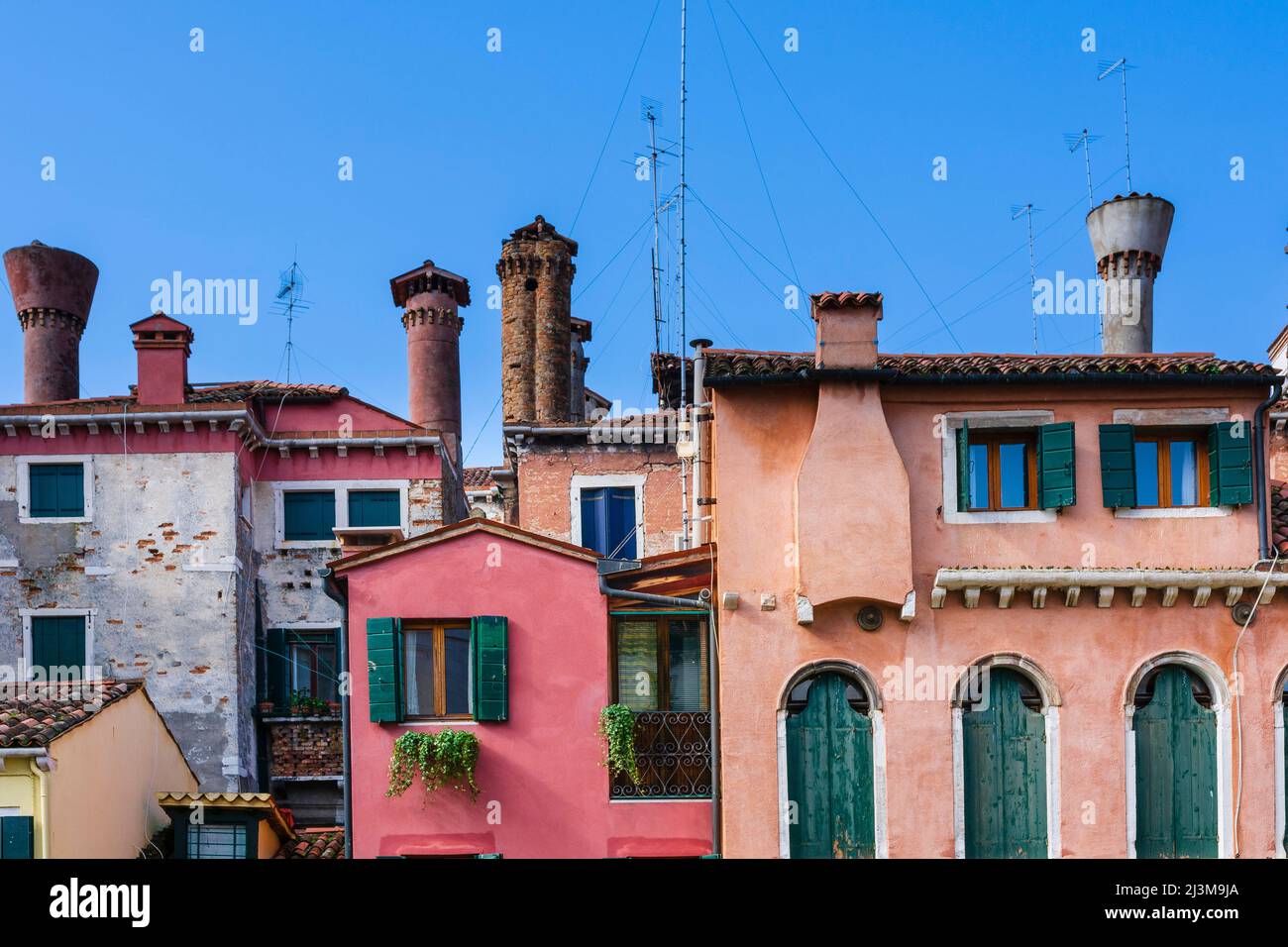 Traditional Venetian buildings in a colourful setting under a blue sky ...