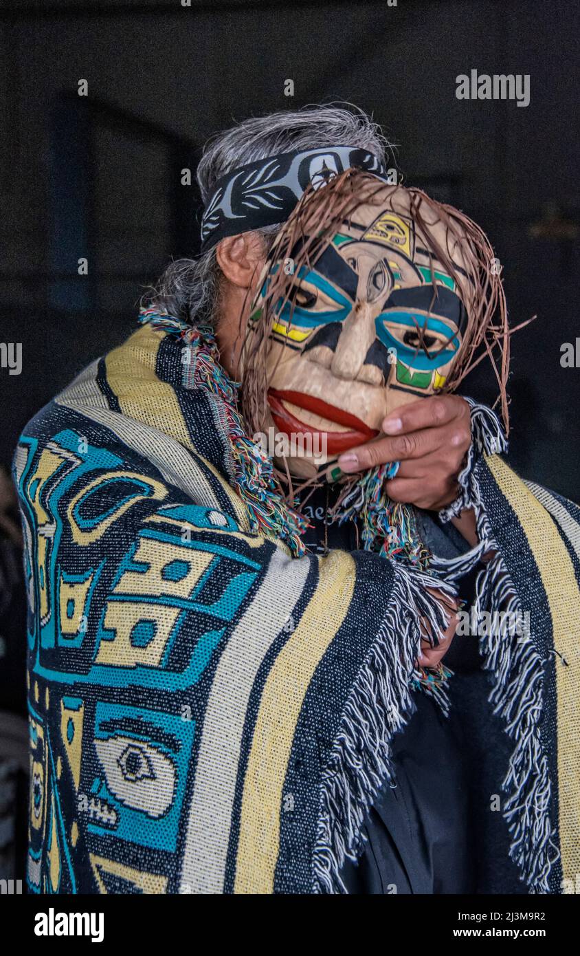 Man stands draped in a blanket with Native Indian design and holding a ...