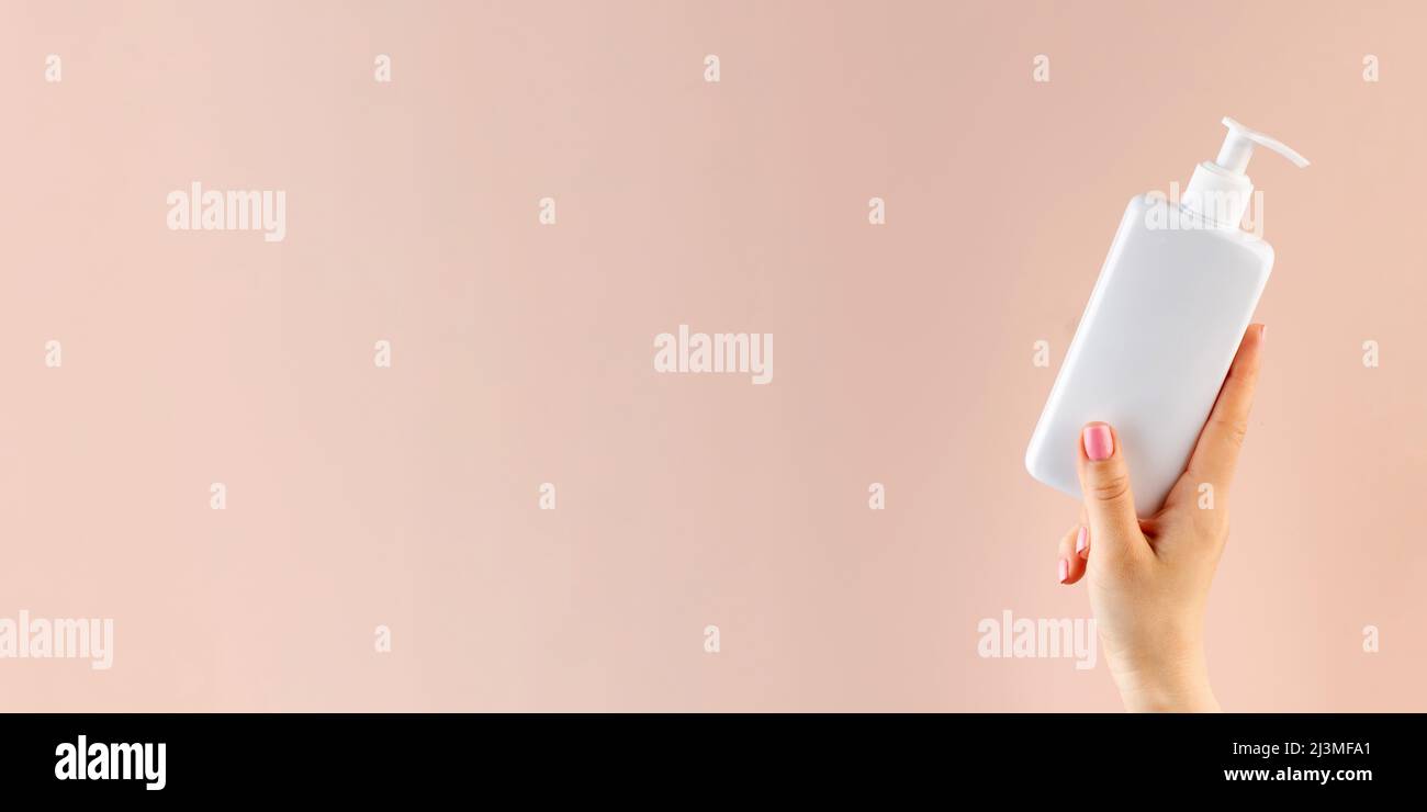 A mockup of a white dispenser with a cosmetic product in a woman's hand ...