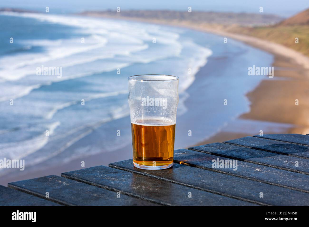 A partly drunk pint of beer on a table at Rhossili Bay, Gower Peninsula ...