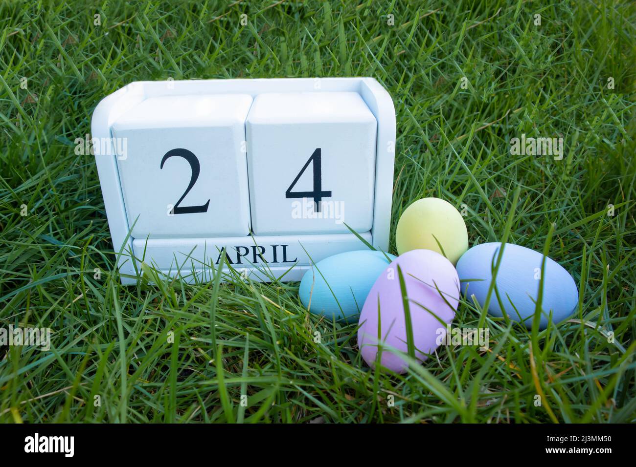 Wooden calendar April 24 stands on the grass, next to Easter eggs Stock ...