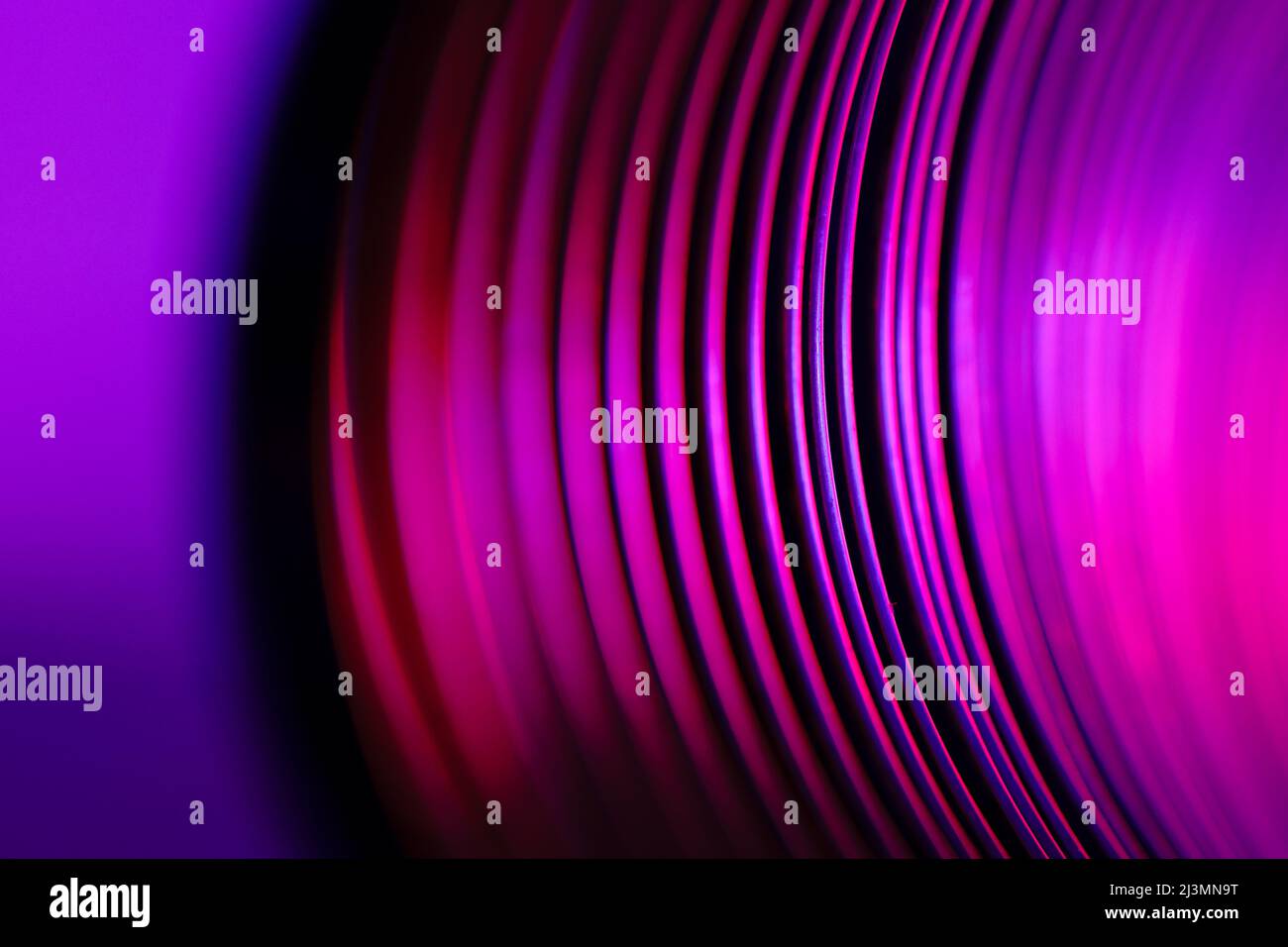 Closeup of coiled metal spring rings in a compressed state in red neon ...