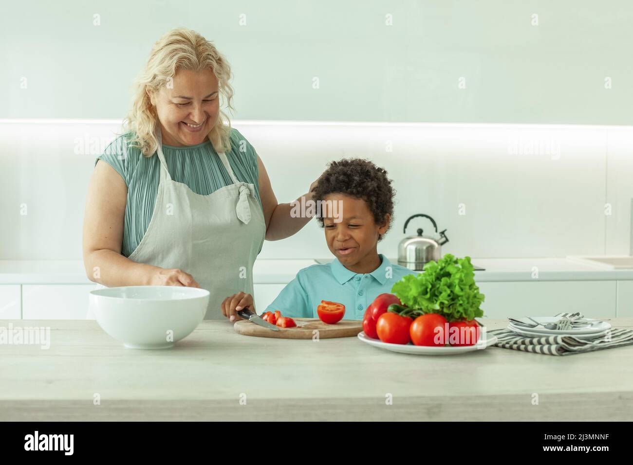 Healthy eating concept. Cute woman and child cooking in white kitchen ...