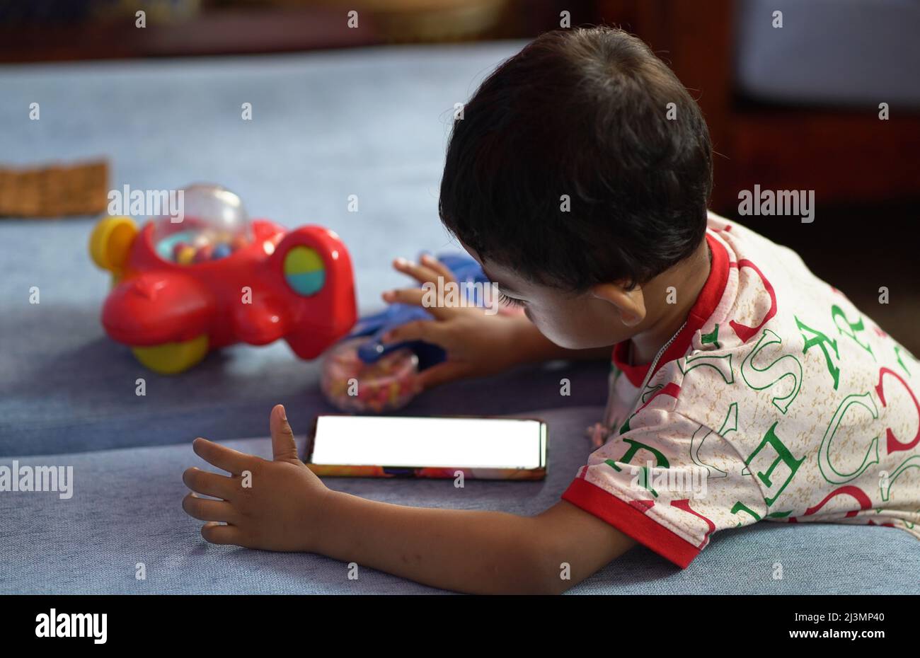 a toddler baby boy engaged in watching and exploring mobile phone ...