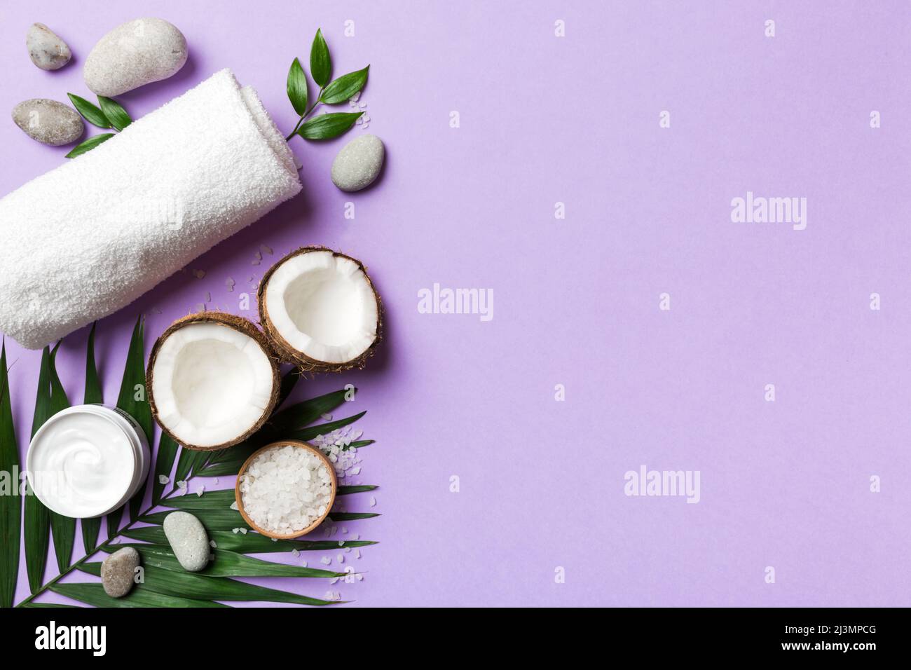 Coconut with jars of coconut oil and cosmetic cream on colored ...