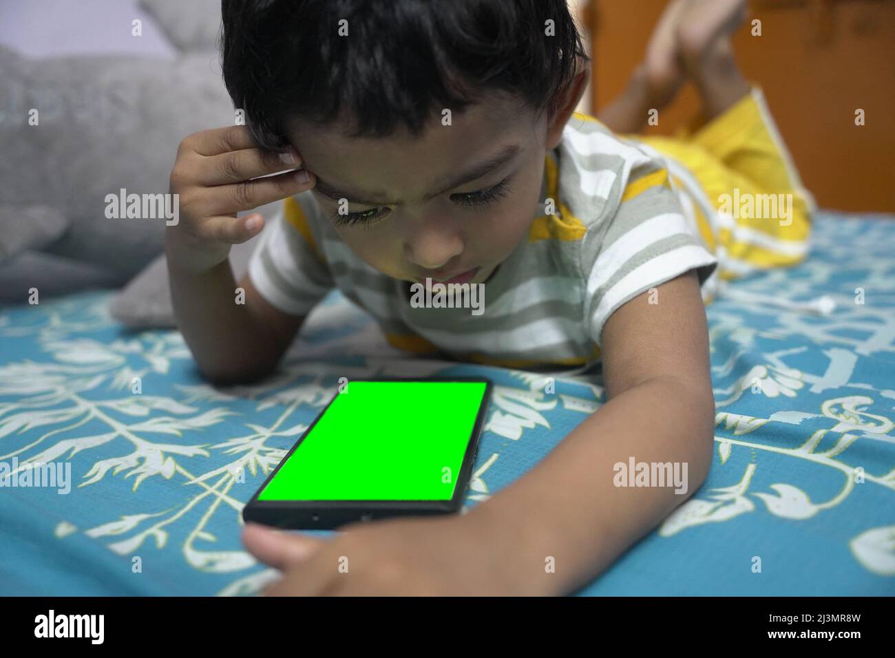a toddler baby boy engaged in watching and exploring mobile phone ...