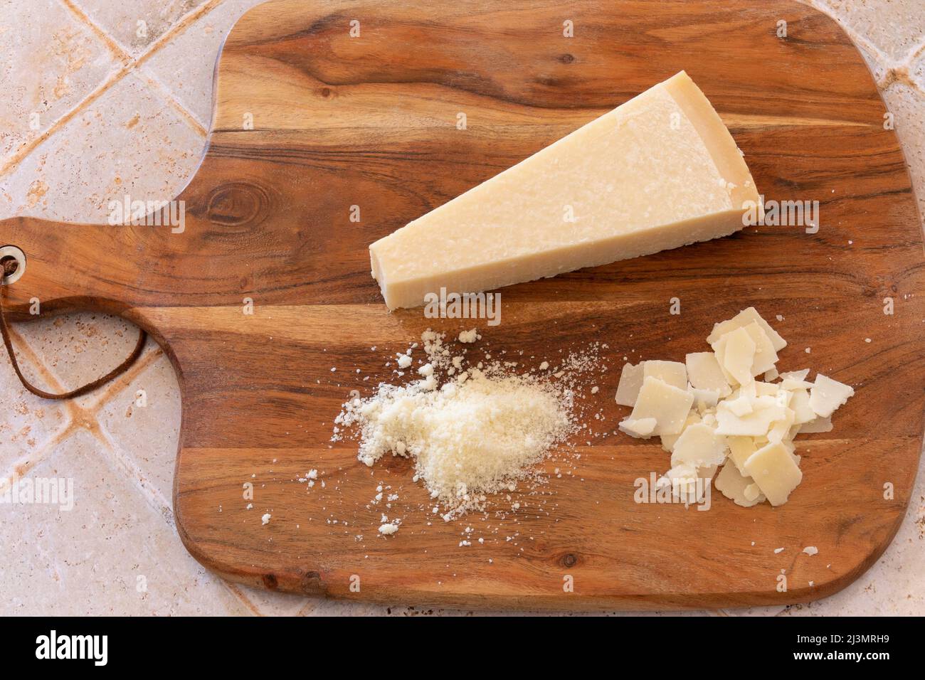 close-up of whole parmesan cheese, shavings, and grated cheese on a ...