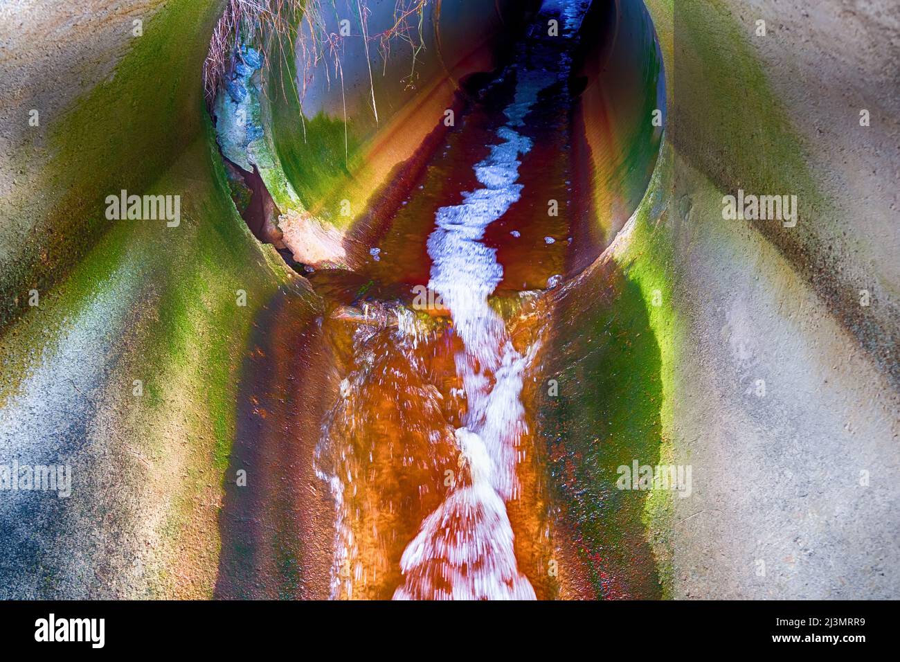 Brown swamp water full of organic substances flows down the pipe and ...