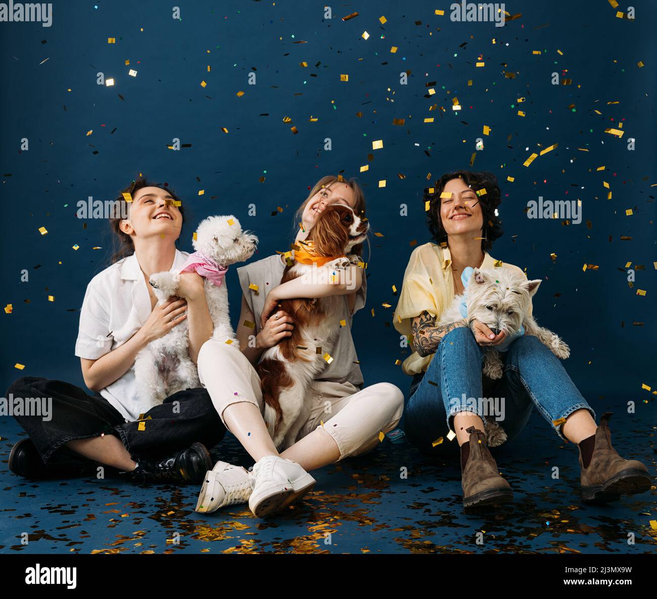 Three laughing women with their dogs sitting on a blue background under ...