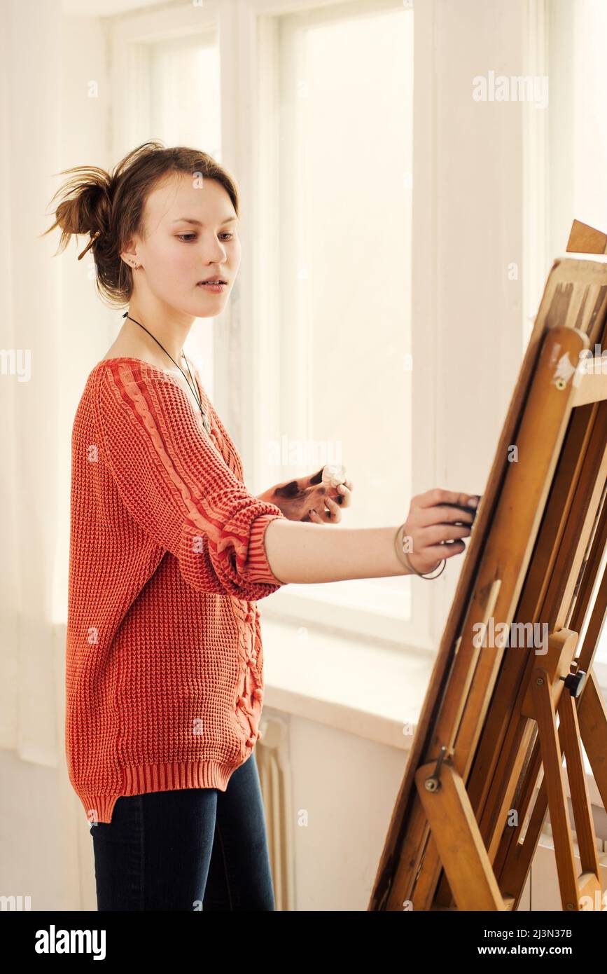 Beautiful woman artist drawing her picture on canvas with oil colors in ...