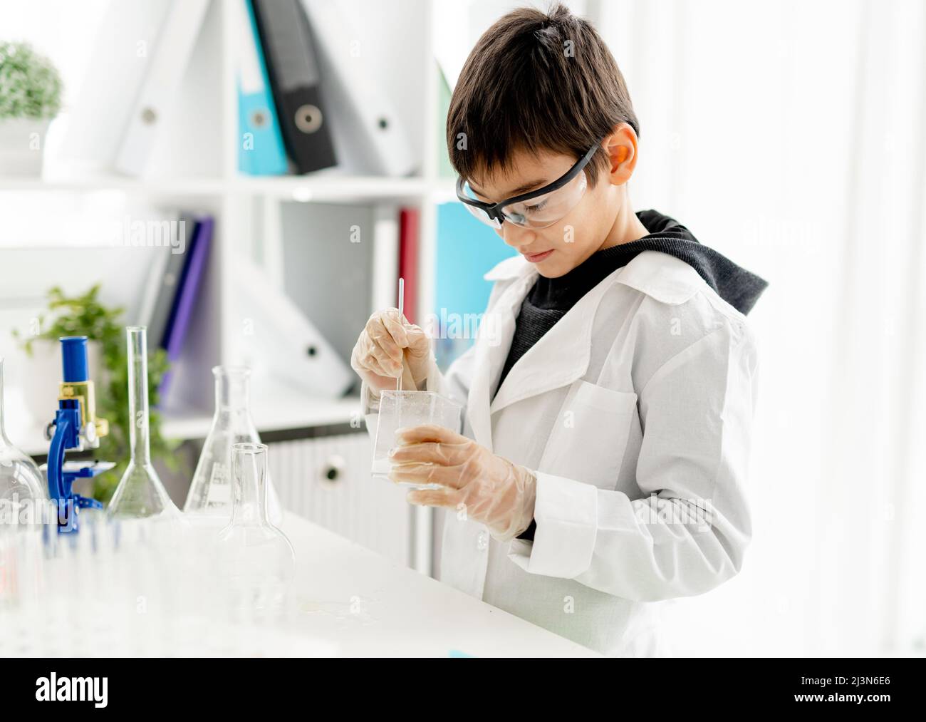 School boy wearing protection glasses doing chemistry experiment in ...