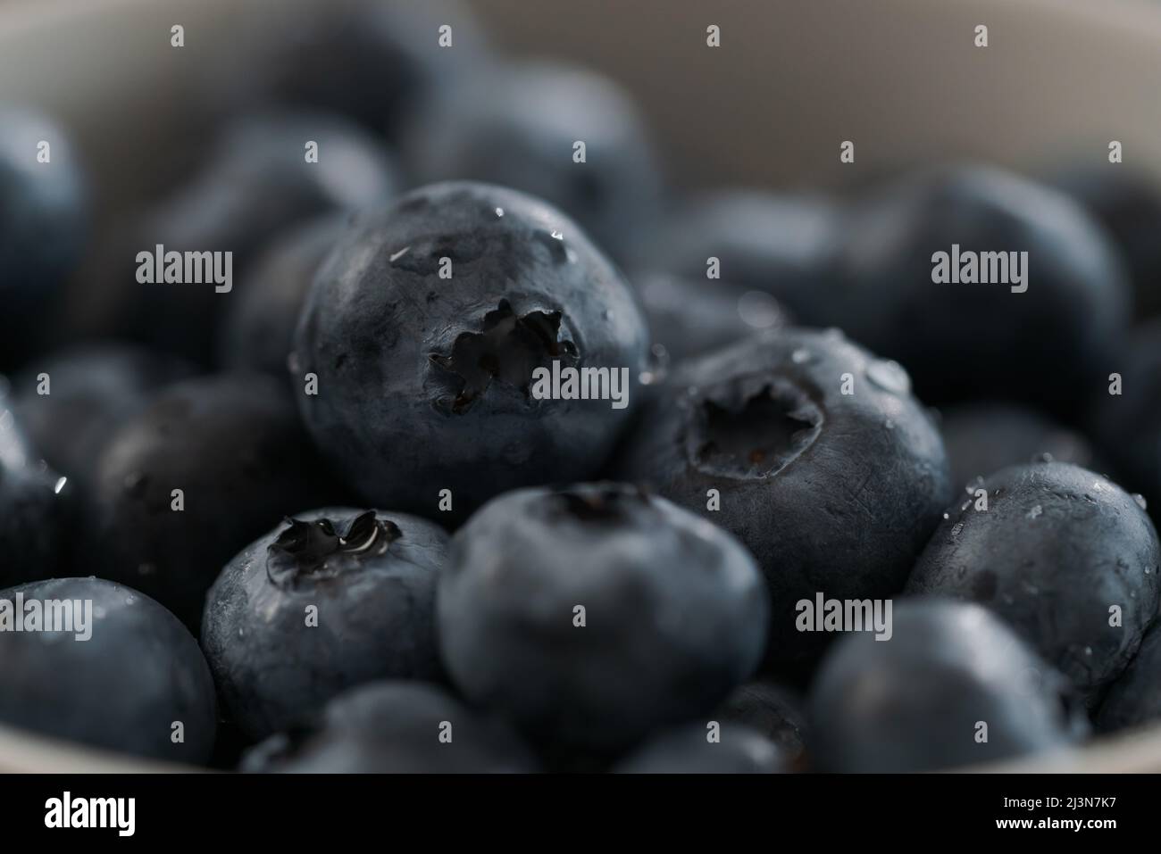 Closeup shot of washed blueberries in white bowl on wood table, shallow ...