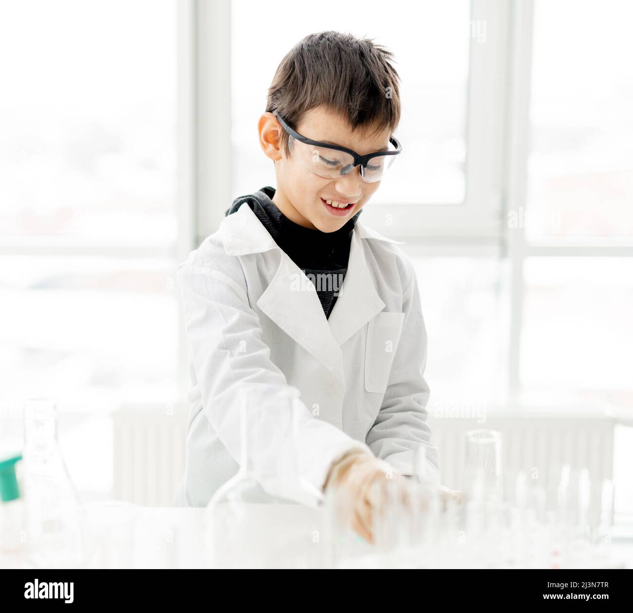 School boy wearing protection glasses doing chemistry experiment in ...