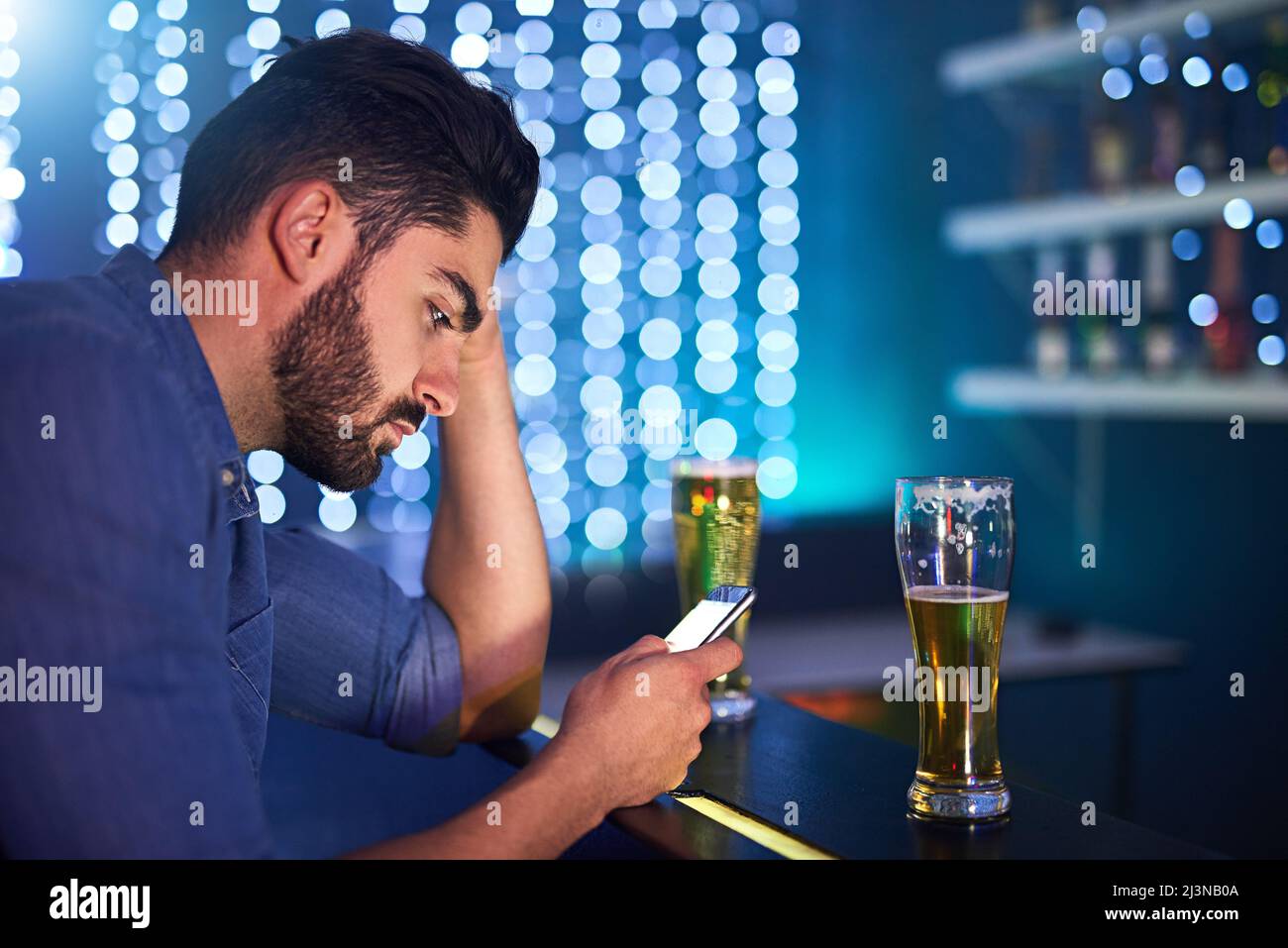 Drunken texts are never a good idea. Shot of a young man looking upset ...