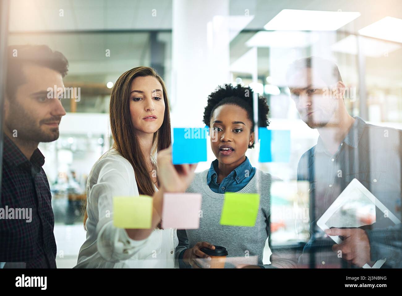 Putting the ideas into focus. Cropped shot of coworkers using sticky ...