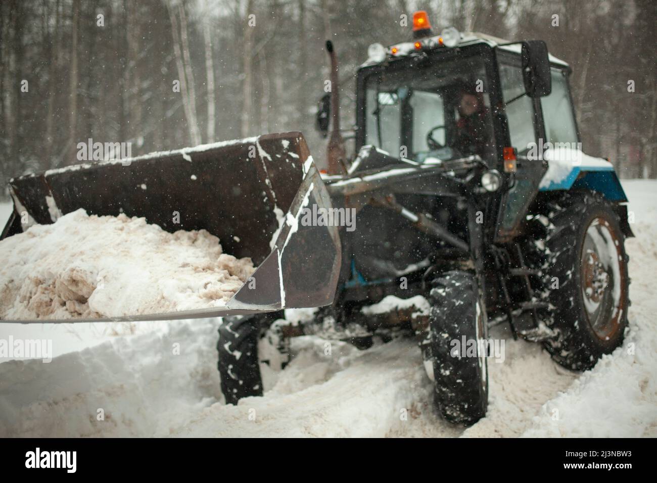 Tractor removes snow. Heavy machinery in winter. Bucket with blocks of ...