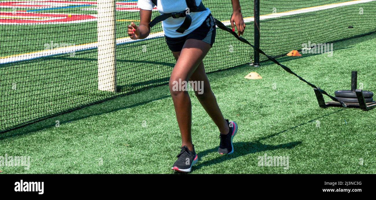 A high school girl is running and pulling a weighted sled for ...