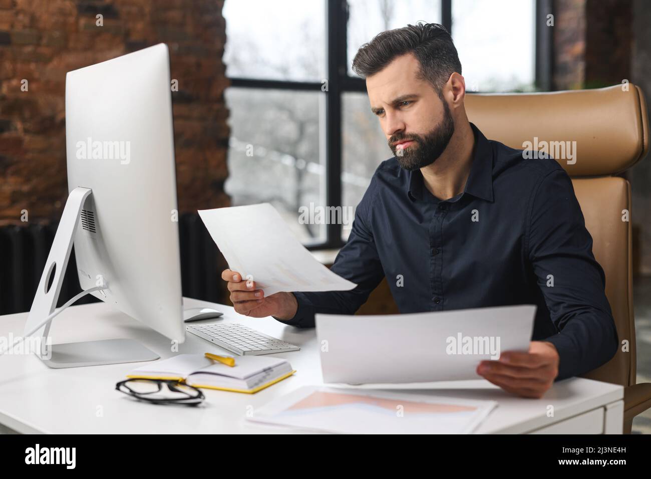 Concentrated caucasian guy is doing paperwork. Man looking through ...