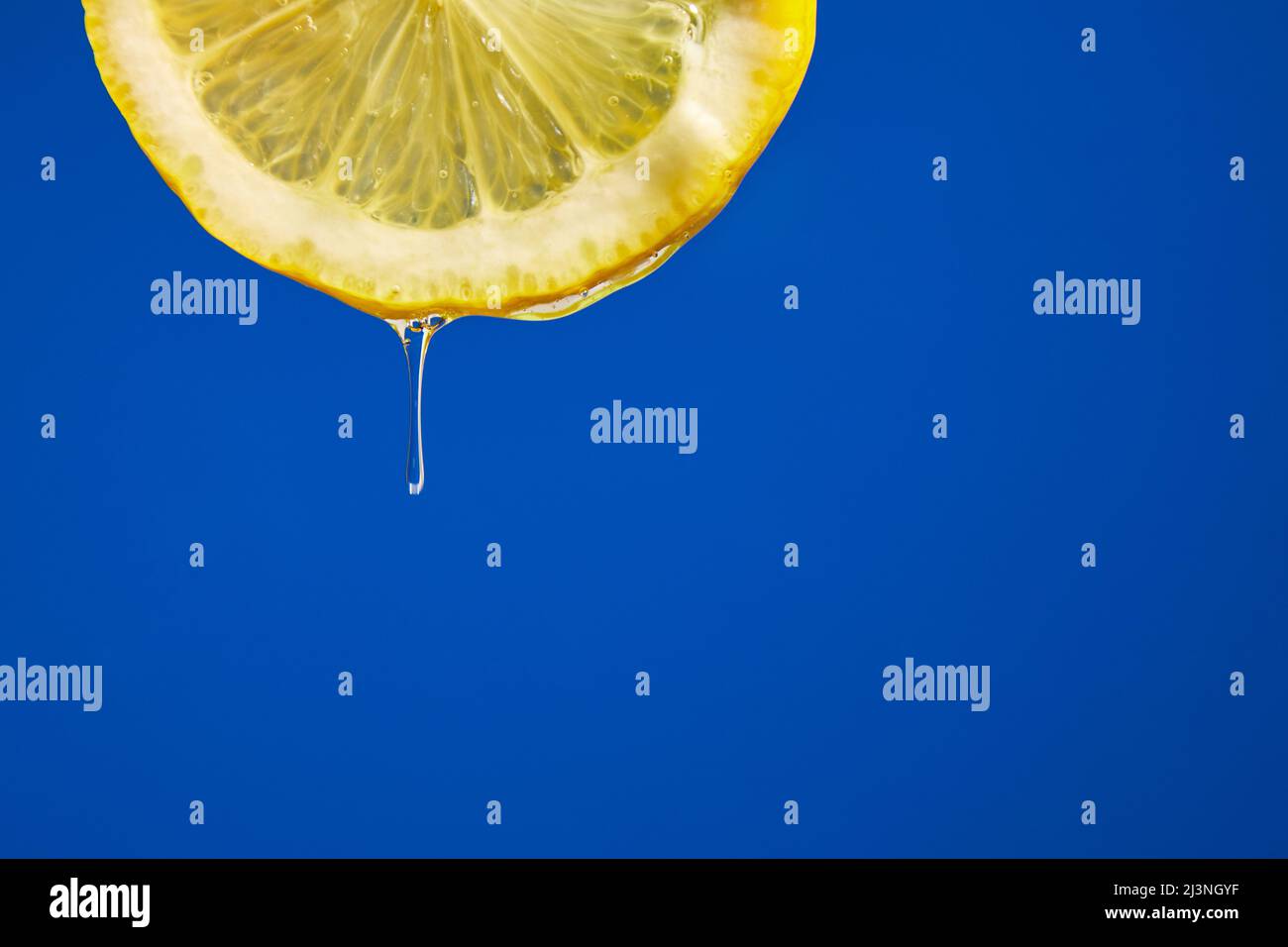 Fresh slice of lemon juice drip on blue background, citrus dripping ...