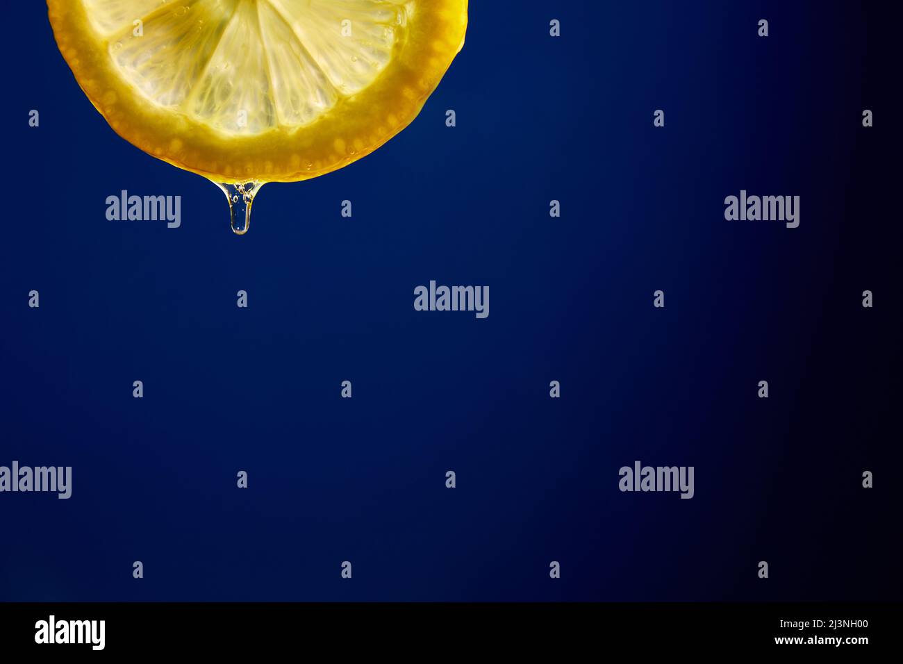 Fresh slice of lemon juice drip on blue background, citrus dripping ...
