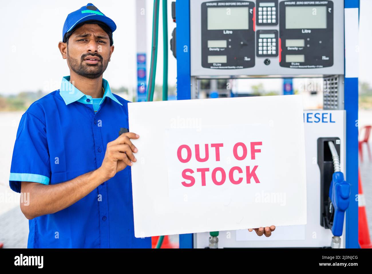Worker at petrol or gas filling sation showing out of stock notice sign ...