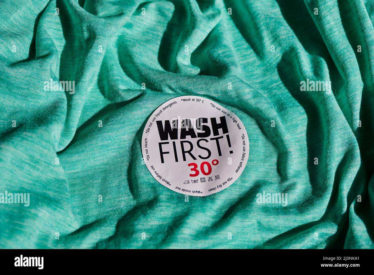 Sticker on a T-shirt with washing instructions and the text "Wash first ...